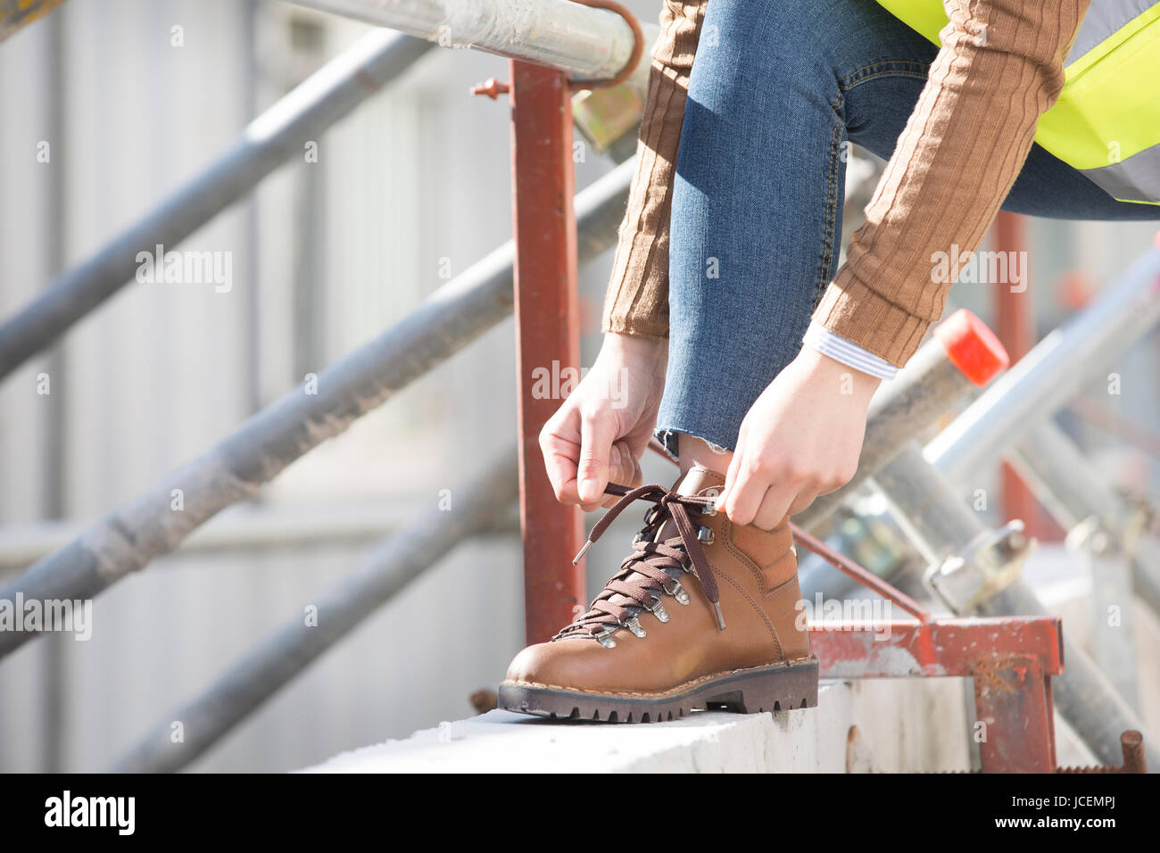 Construction worker tying shoestring Stock Photo - Alamy