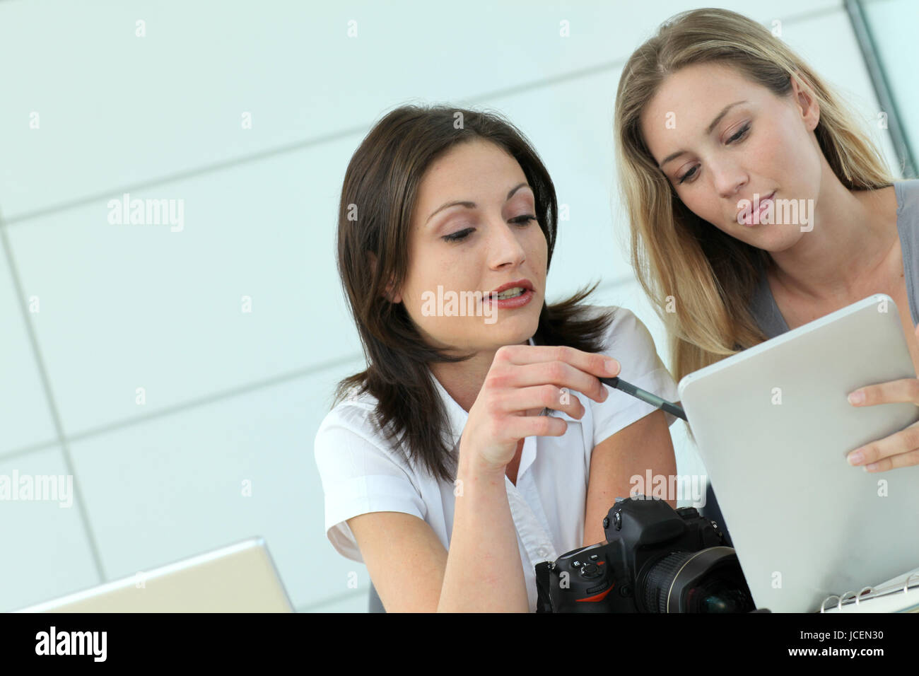 Women photographers working in office with tablet Stock Photo - Alamy