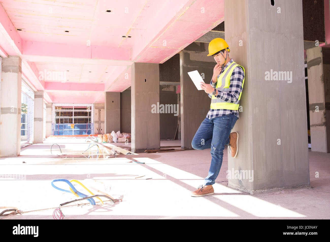 Construction worker with tablet leaning Stock Photo - Alamy