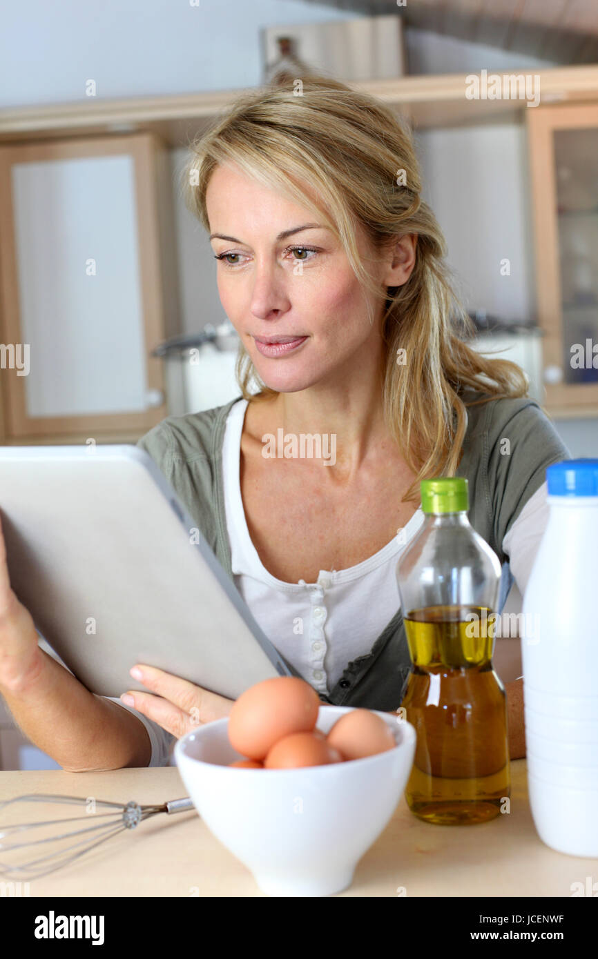 Woman in kitchen looking at dessert recipe on internet Stock Photo - Alamy