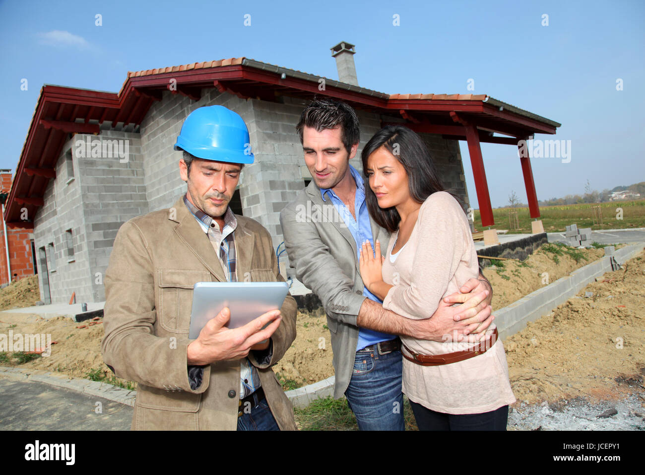 Entrepreneur showing house under construction to couple Stock Photo - Alamy