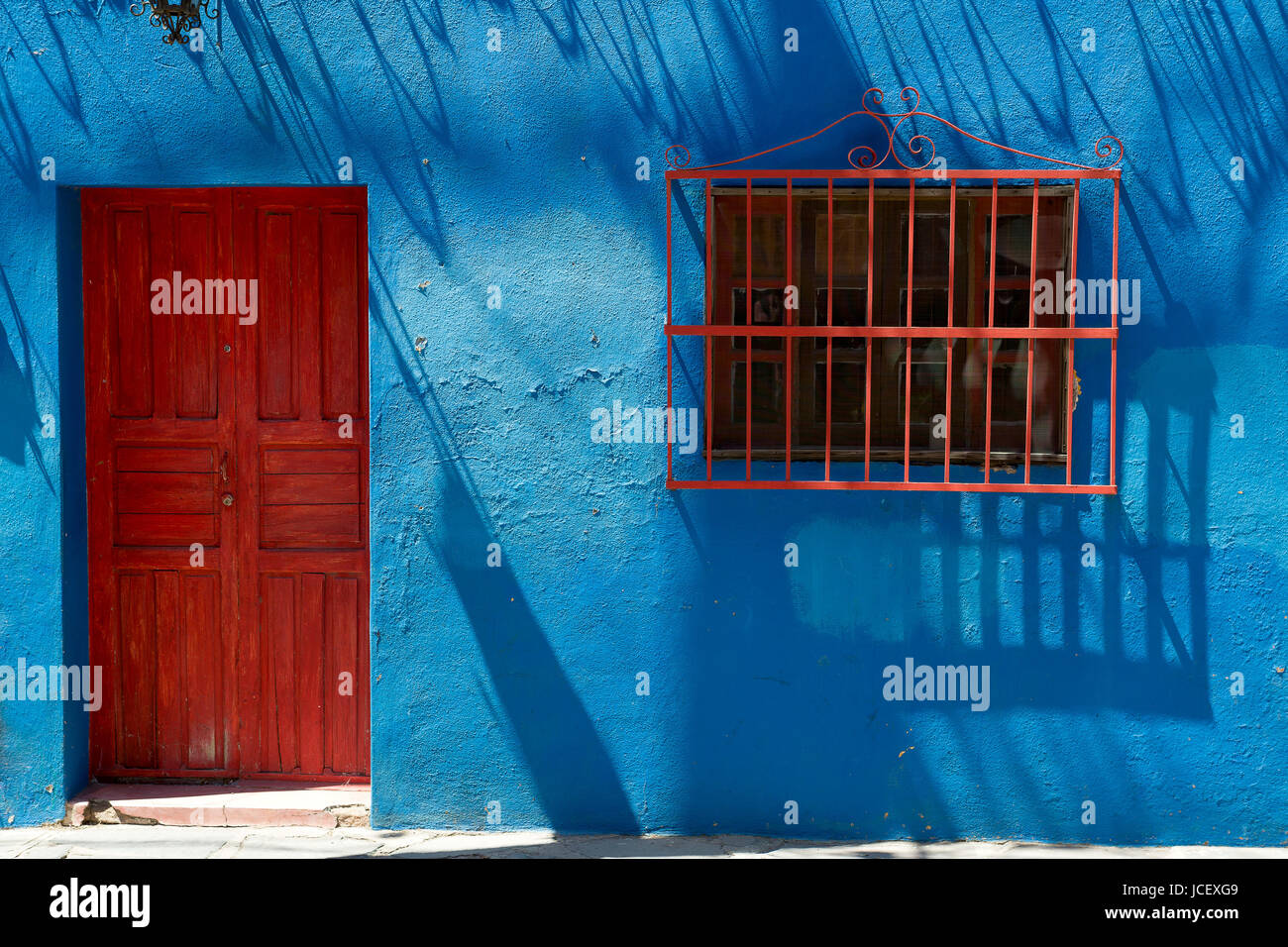 bright blue building with red door and window grill Stock Photo - Alamy