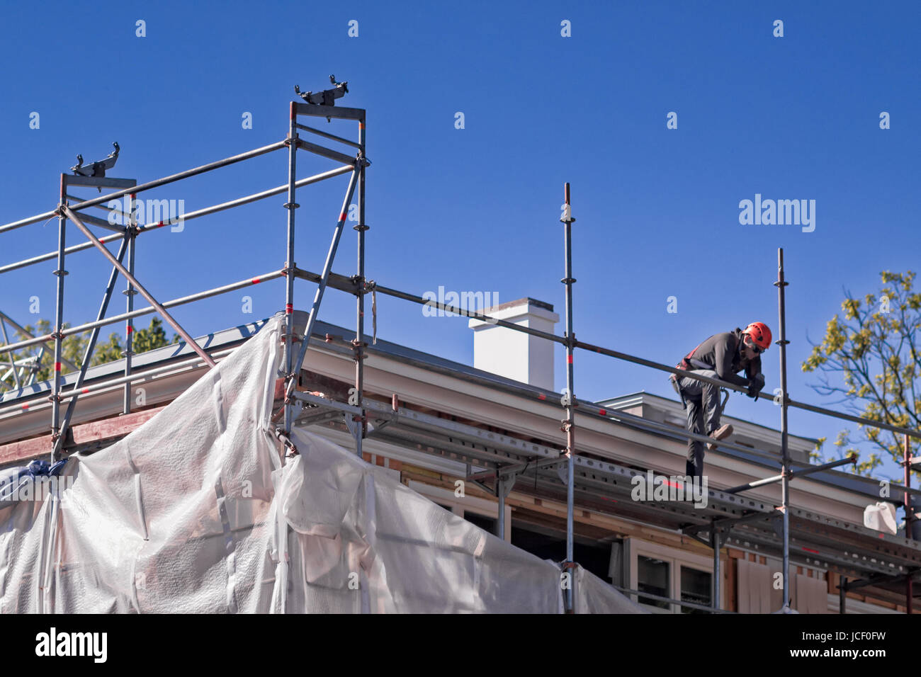 A builder looks down and waits for supplies at a bulding site in ...