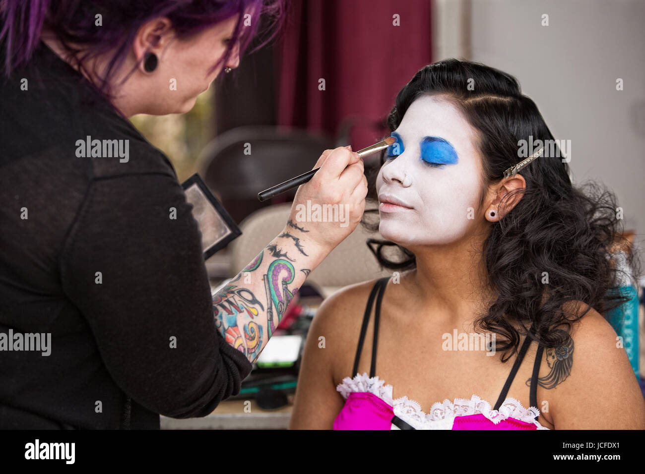 Young beautiful clown getting eye shadow backstage Stock Photo - Alamy