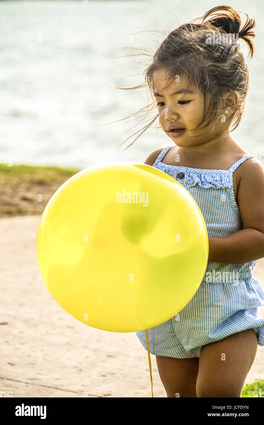 A little girl holds on to her balloon on a windy day Stock Photo - Alamy
