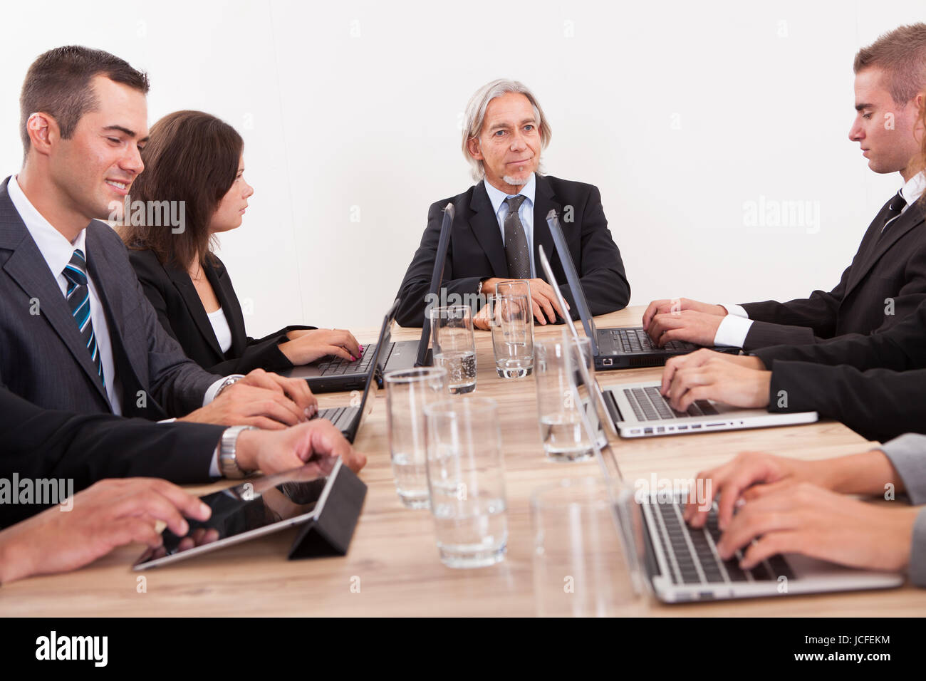 Businesspeople Sitting At Conference Table Using Laptop Stock Photo - Alamy