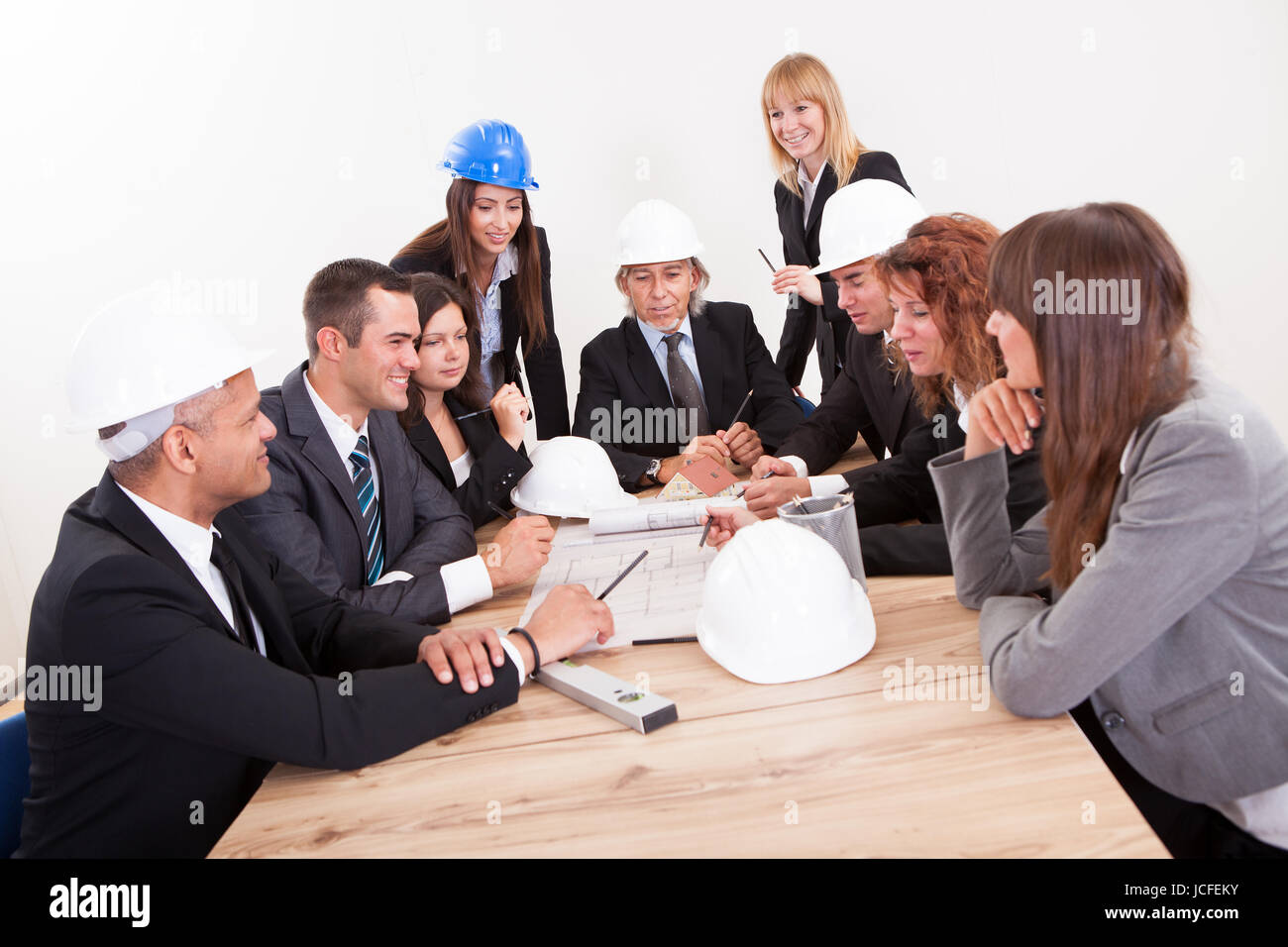 Engineers Discussing About A New Project Around A Table Pointing At A ...
