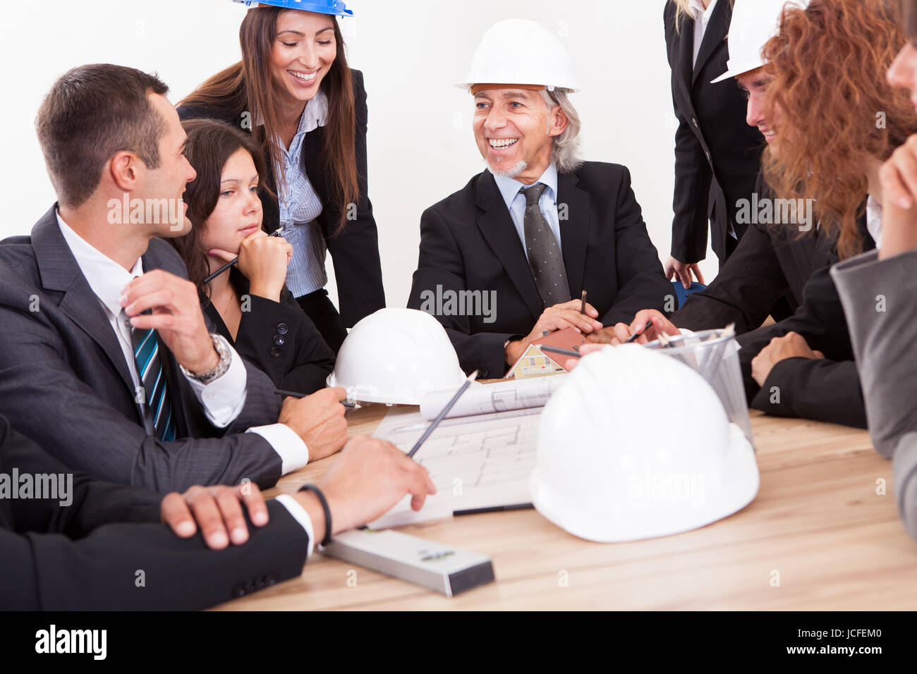 Engineers Discussing About A New Project Around A Table Pointing At A ...