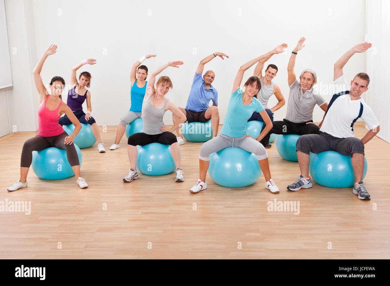 Large group of diverse people in a pilates class exercising in a gym ...