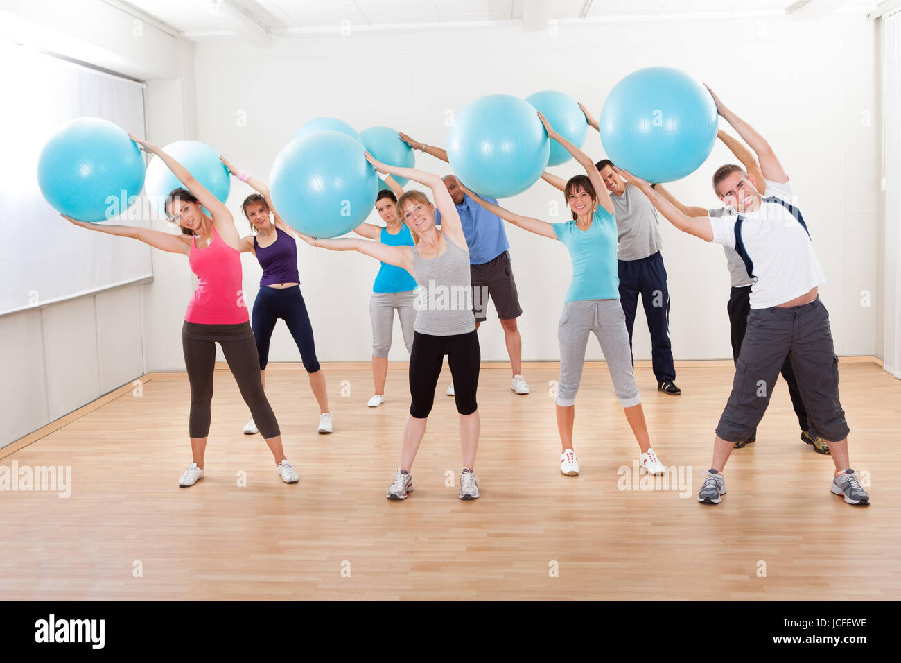 Large group of diverse people in a pilates class exercising in a gym ...