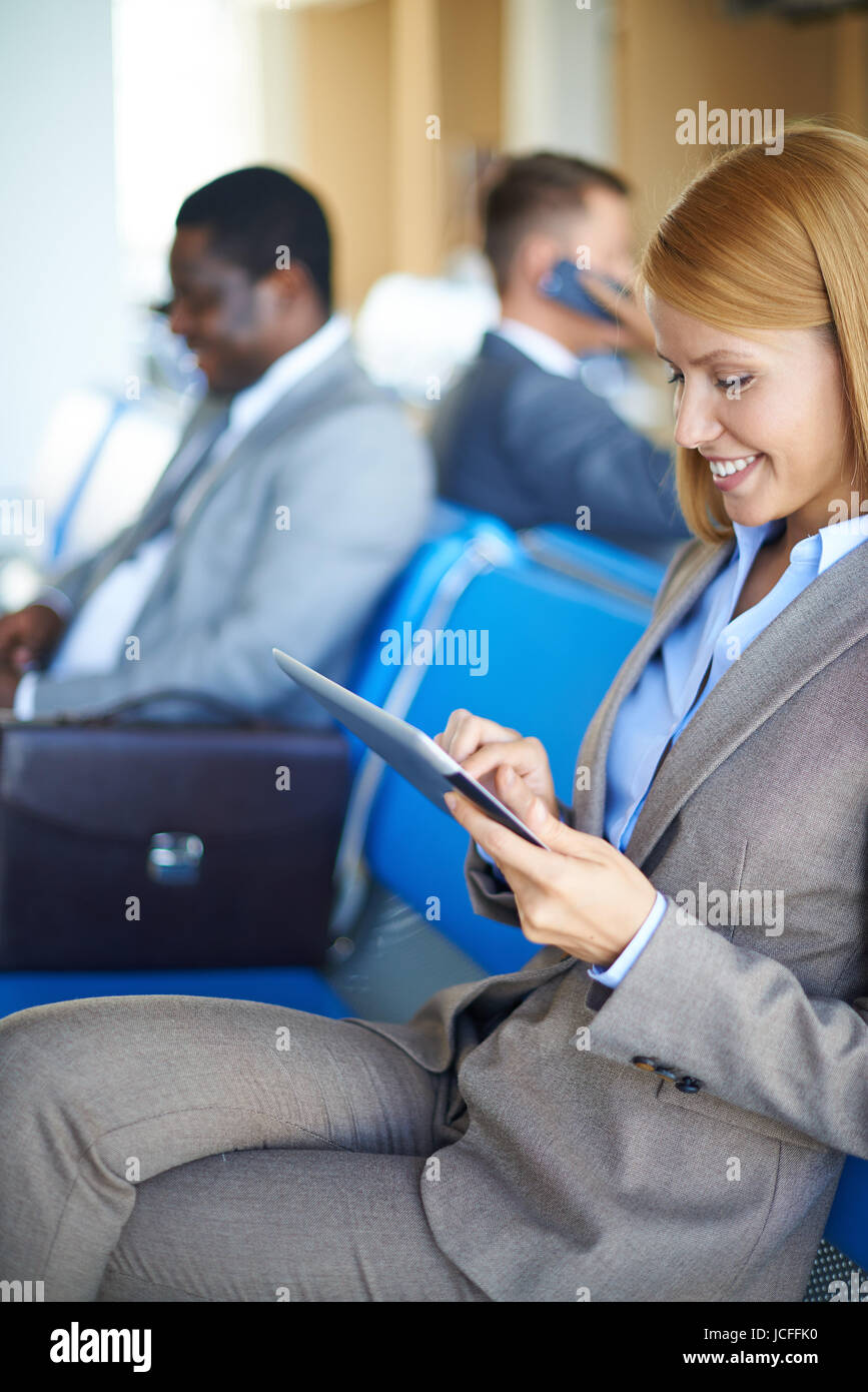 Female employee networking in airport with two men sitting on ...