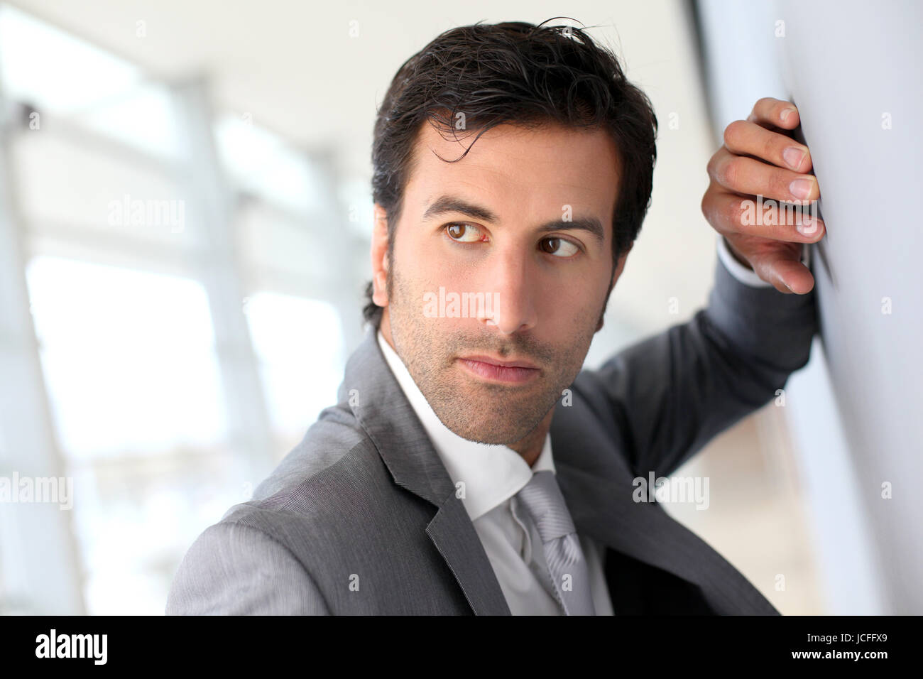 Businessman standing against wall Stock Photo - Alamy