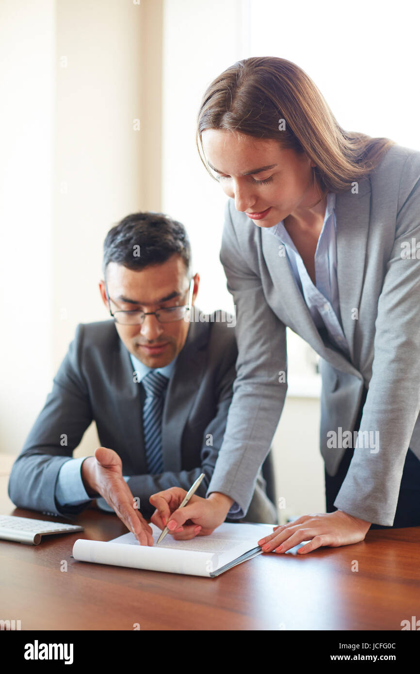 Businessman explaining to his secretary how to fill in the paper in ...