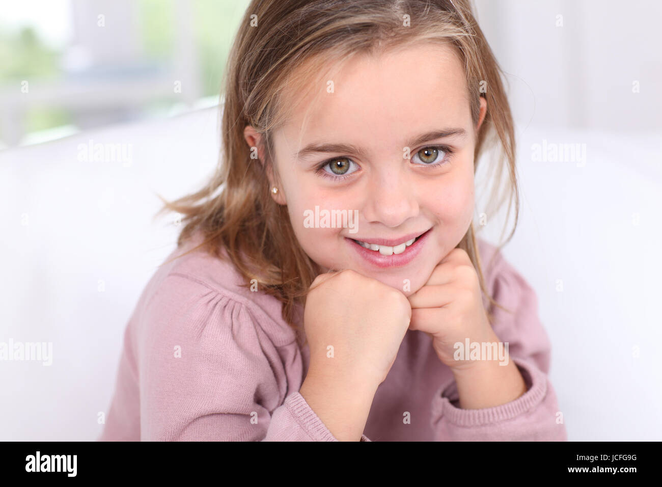 Portrait of cute little girl with hands on chin Stock Photo - Alamy