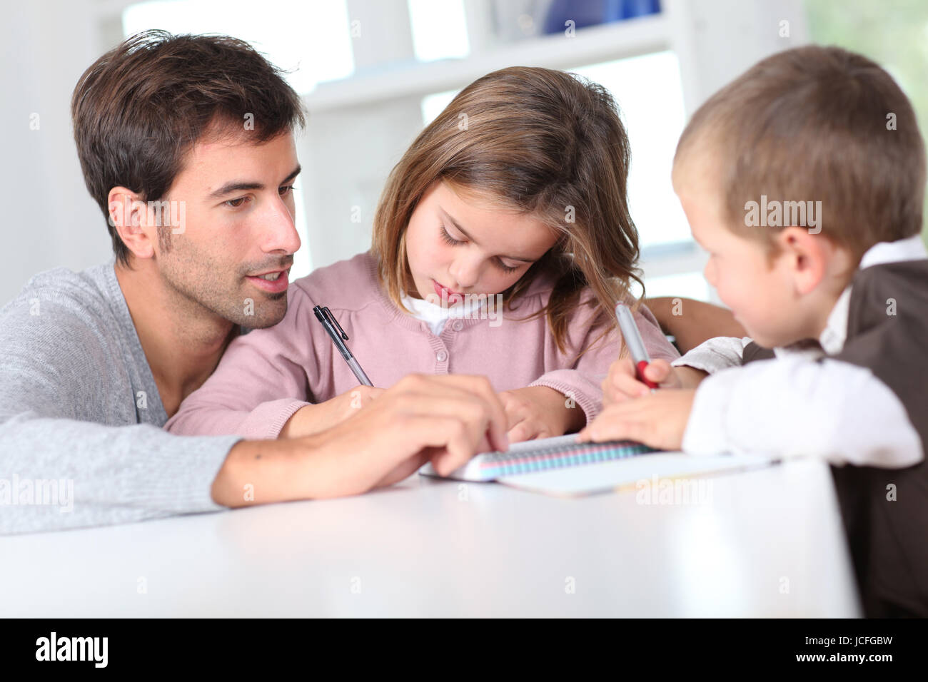 Man helping kids with homework Stock Photo - Alamy