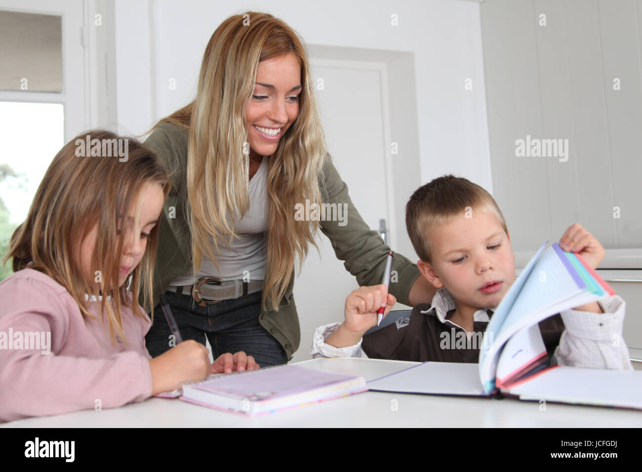 Woman helping kids with homework Stock Photo - Alamy