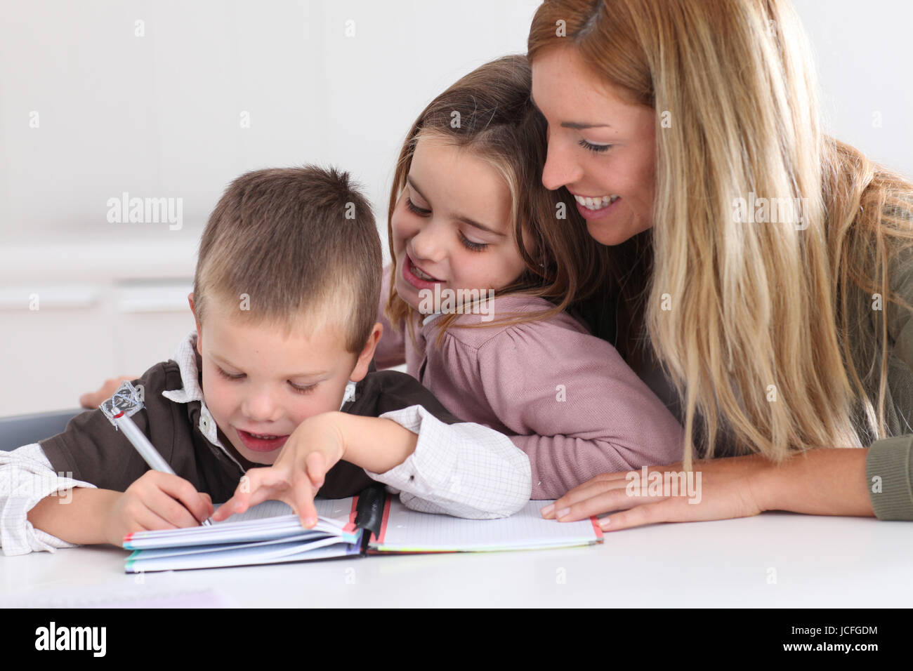 Woman helping kids with homework Stock Photo - Alamy