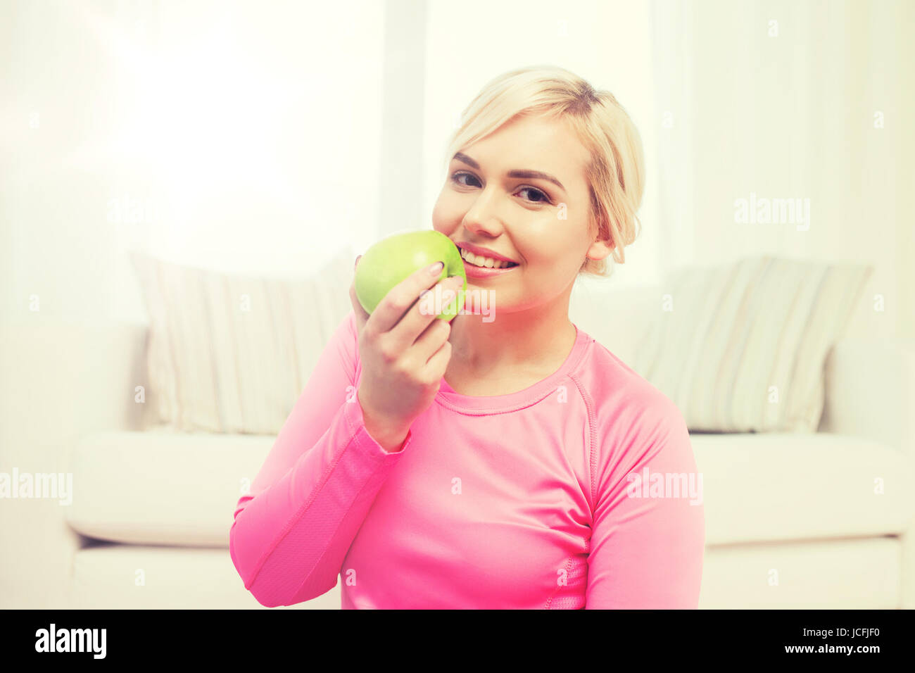 happy woman eating apple at home Stock Photo - Alamy