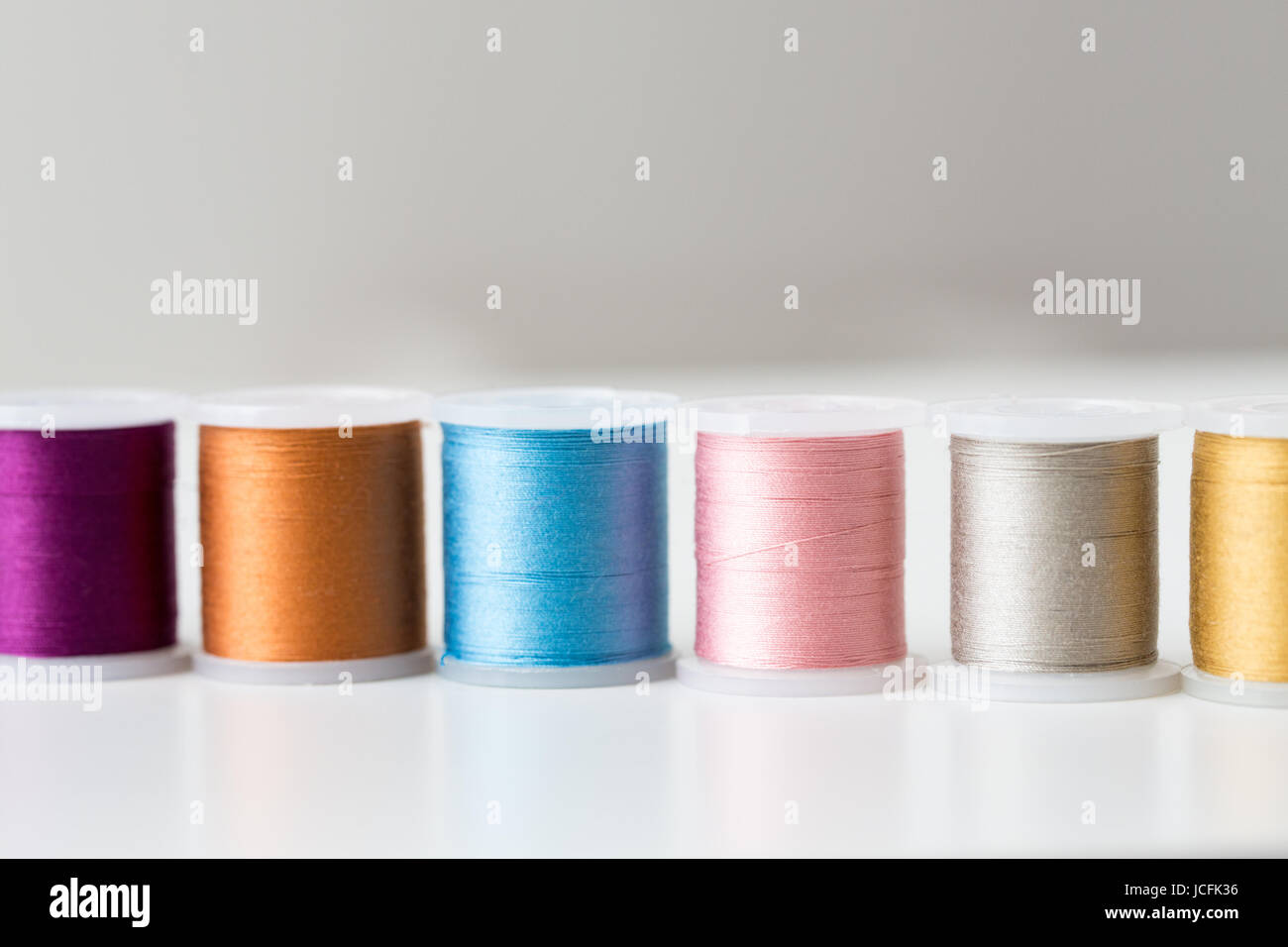 row of colorful thread spools on table Stock Photo - Alamy