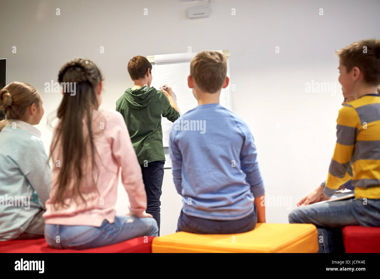 student boy with marker writing on flip board Stock Photo - Alamy