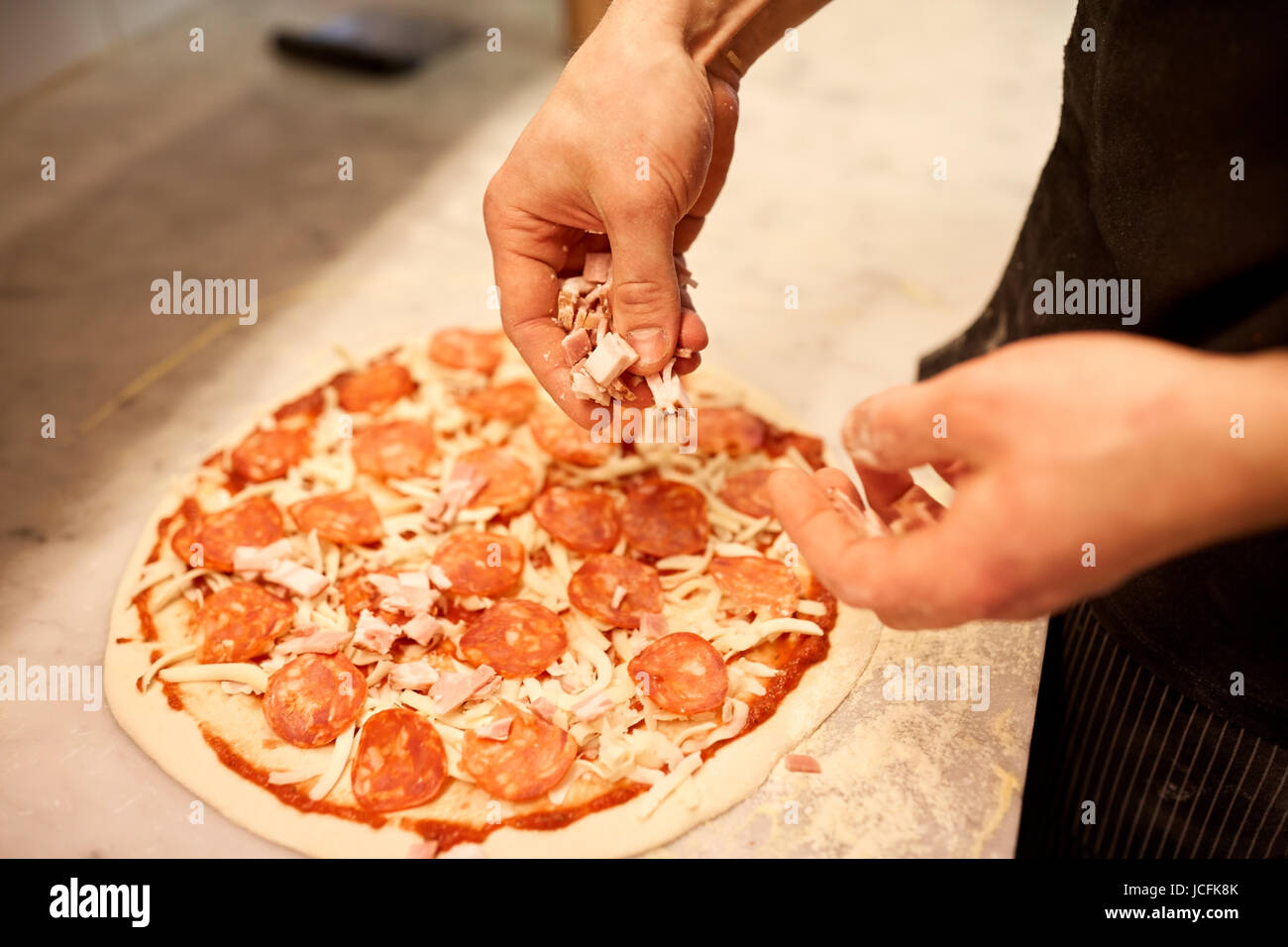 cook hands adding ham to salami pizza at pizzeria Stock Photo - Alamy