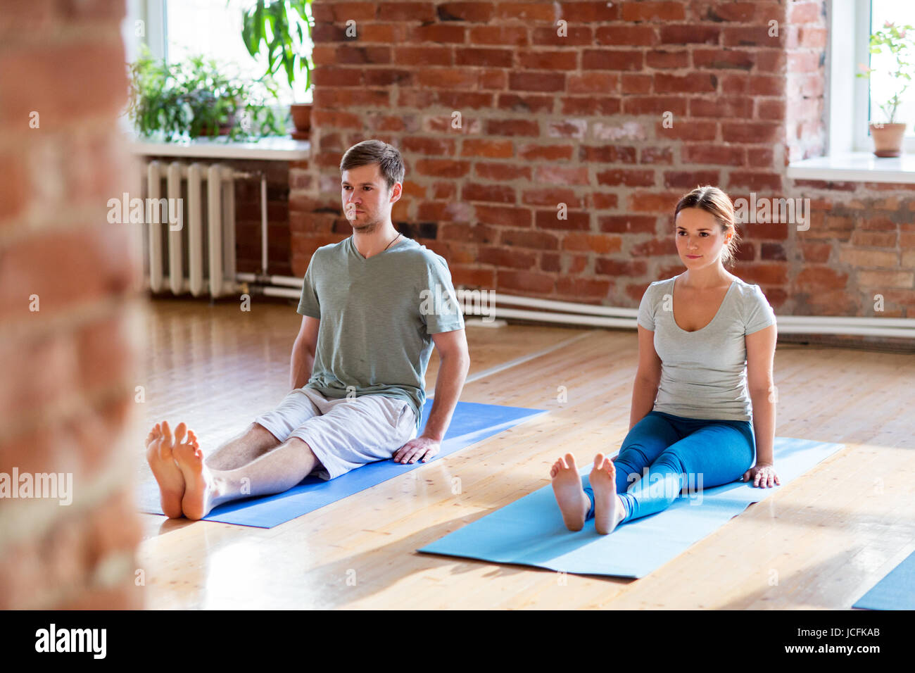 man and woman doing yoga staff pose at studio Stock Photo - Alamy