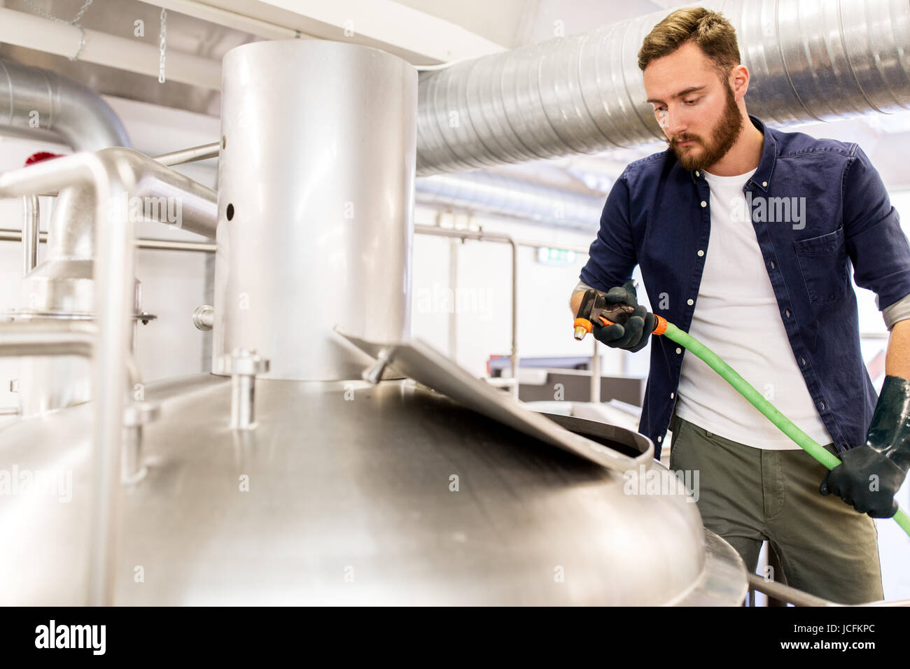 man with hose working at craft beer brewery kettle Stock Photo - Alamy