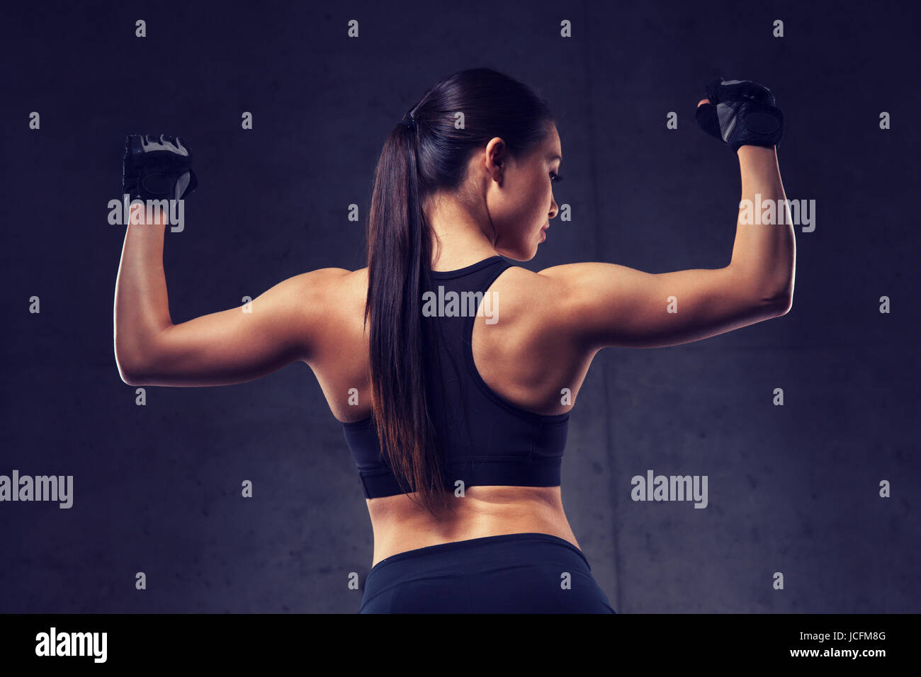 young woman flexing muscles in gym Stock Photo - Alamy