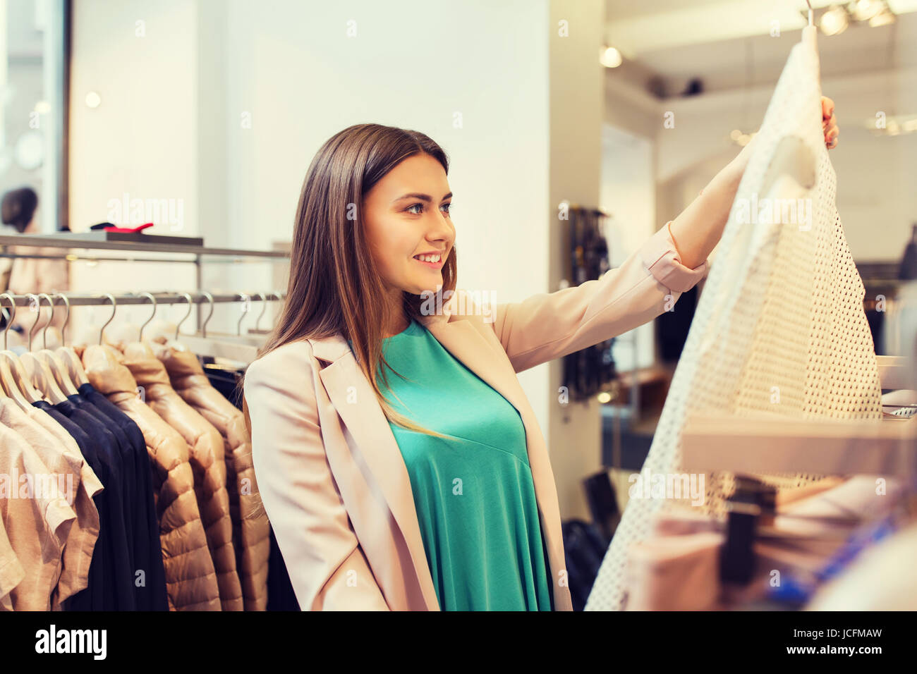 happy young woman choosing clothes in mall Stock Photo - Alamy