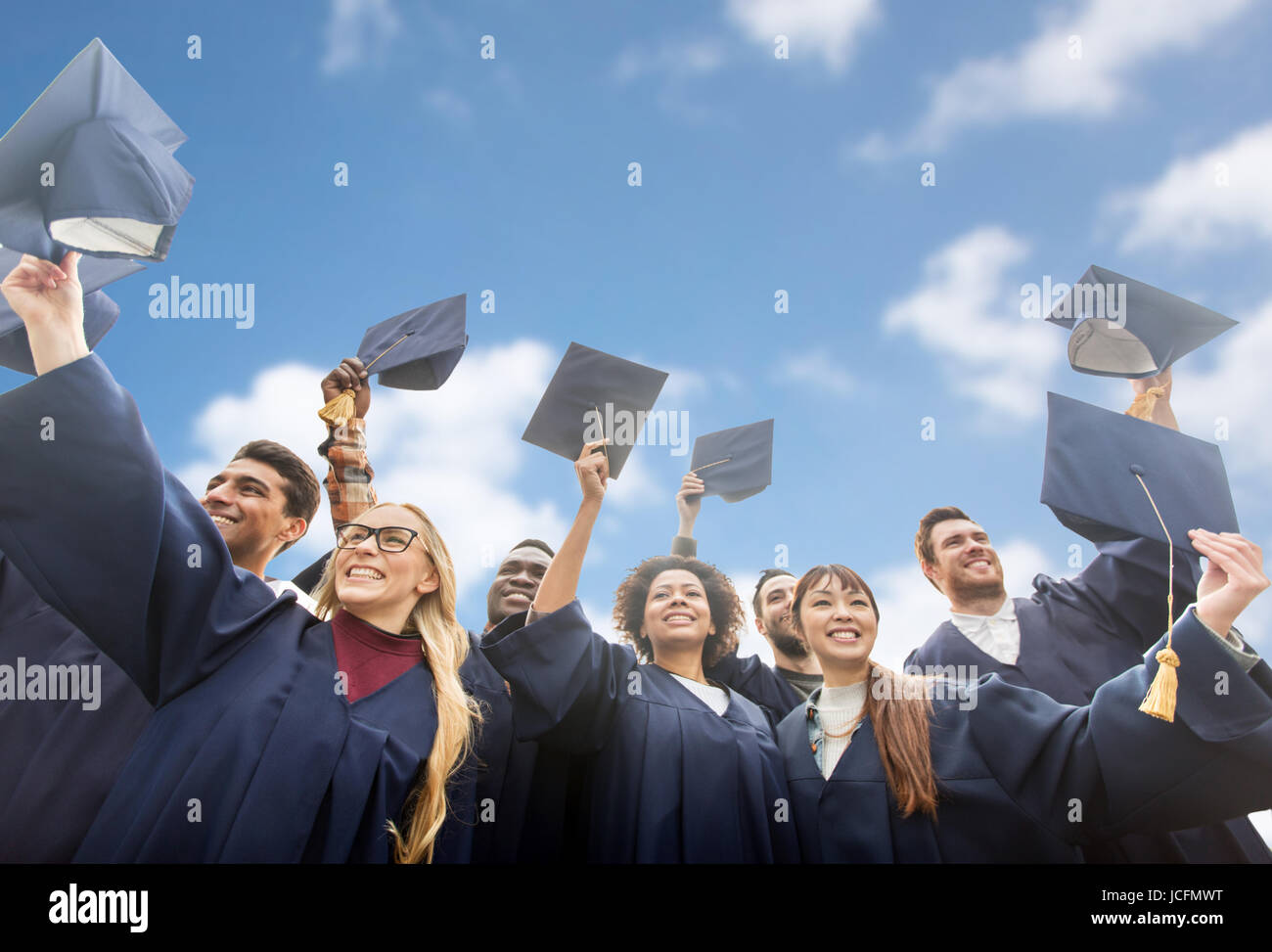happy bachelors waving mortar boards over sky Stock Photo - Alamy