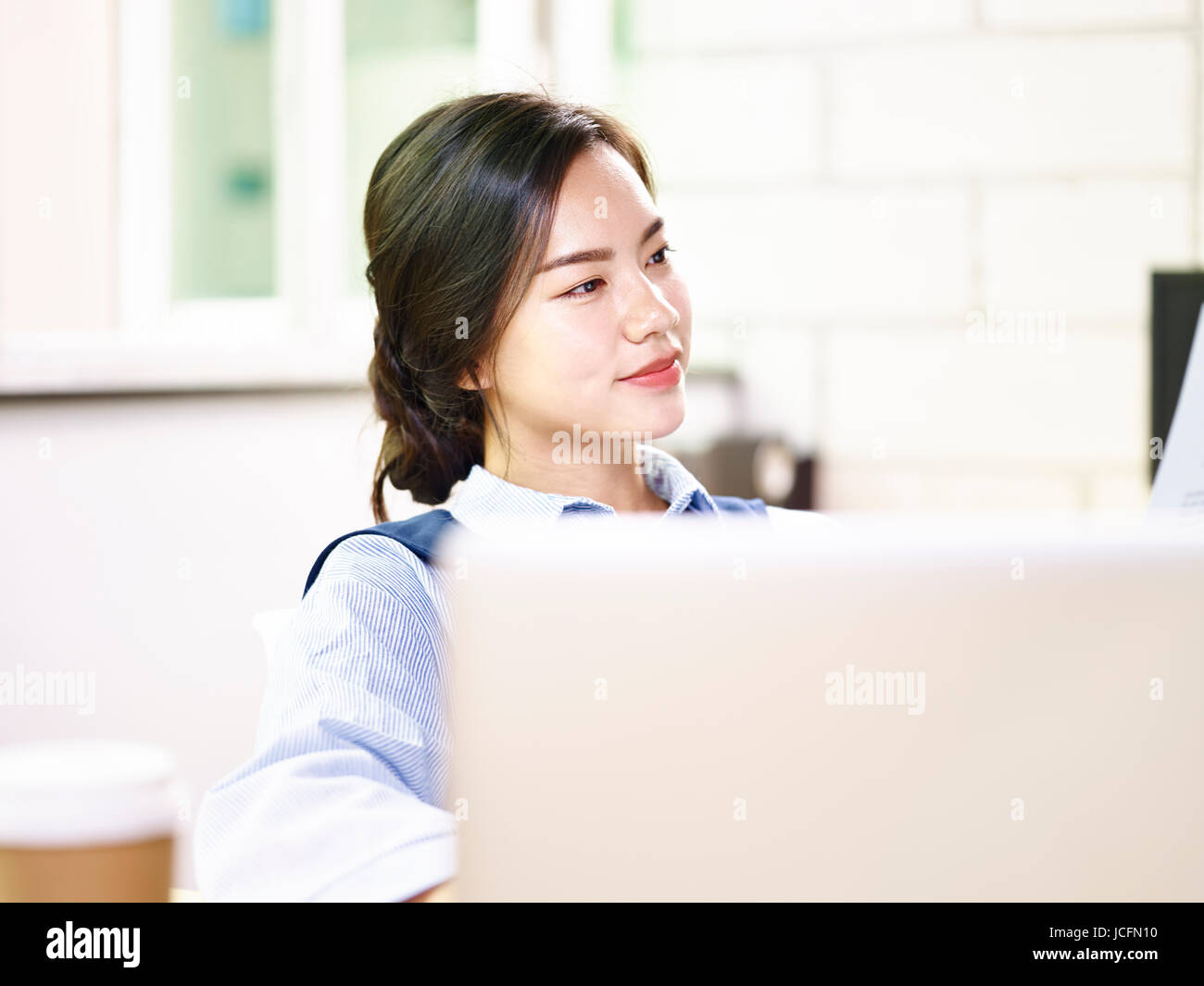 young asian business woman sitting in front of laptop computer thinking ...