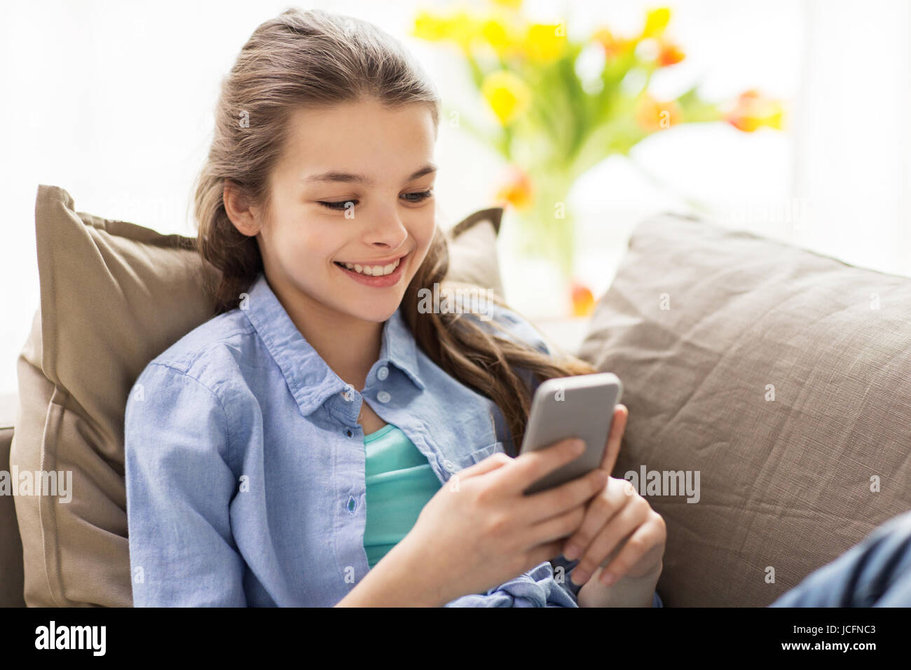smiling girl texting on smartphone at home Stock Photo - Alamy