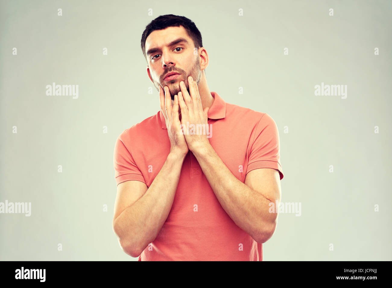 young man touching his face over gray background Stock Photo - Alamy