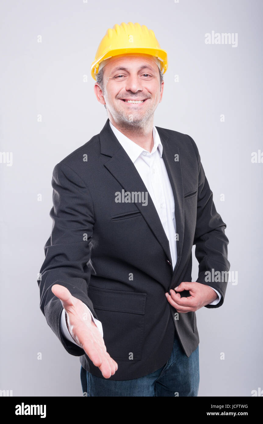 Handsome contractor wearing helmet offering hand shake and smiling on ...