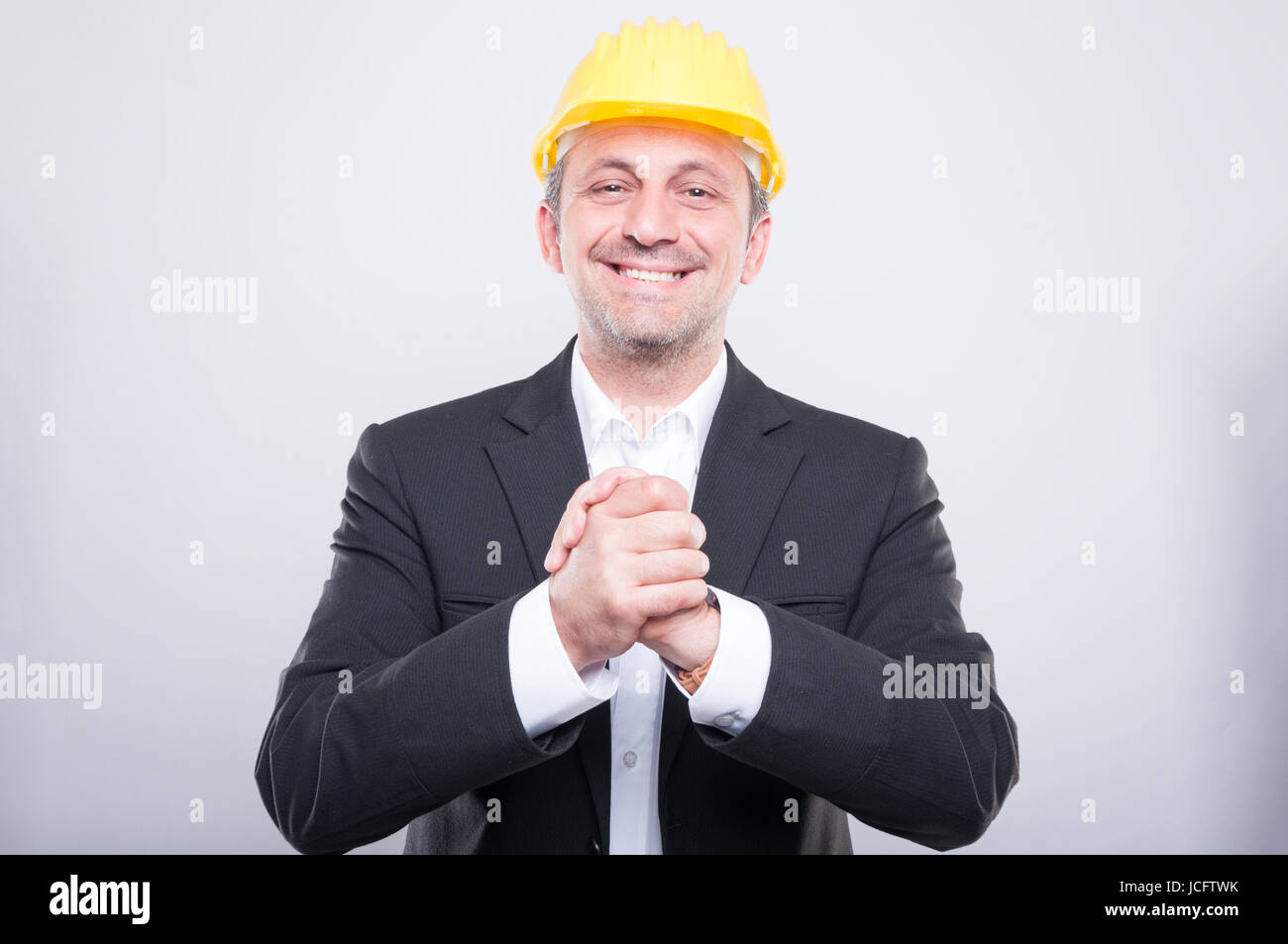 Handsome contractor wearing helmet gesturing hand shake and smiling on ...