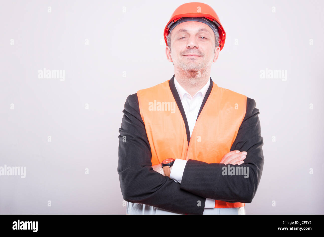Portrait of foreman wearing hardhat and vest standing with arms crossed ...