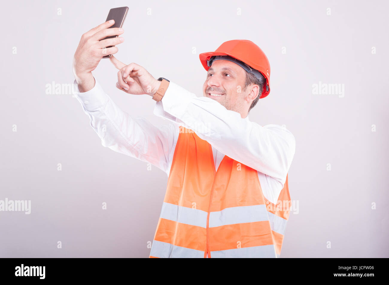Foreman wearing reflective vest making selfie and smiling on grey ...