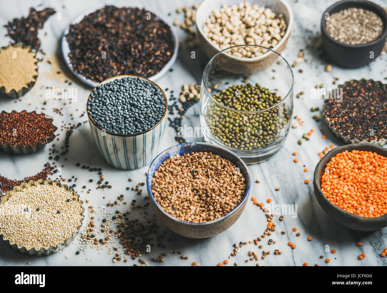 Various raw uncooked grains, beans, cereals in bowls, cups and glass ...