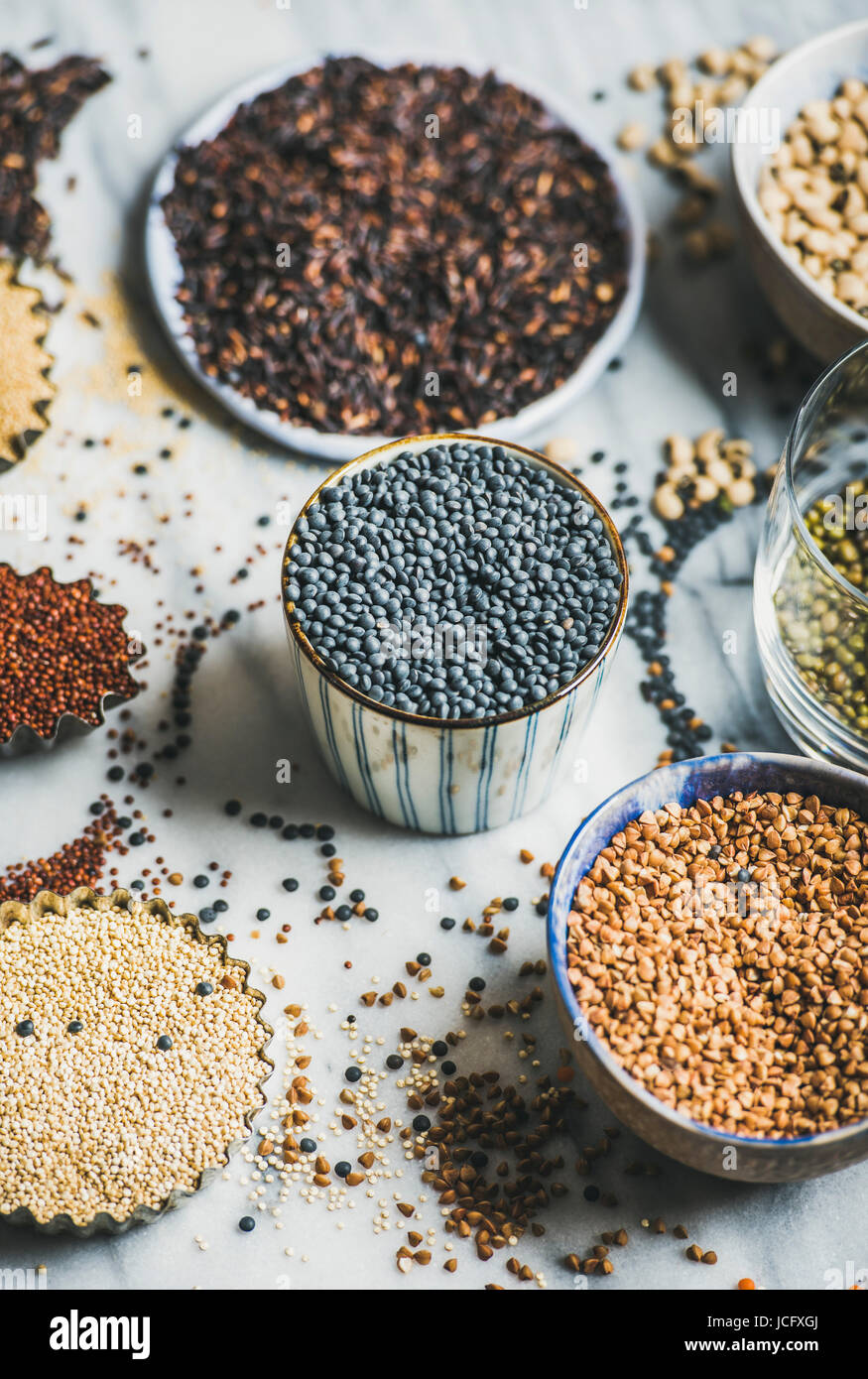 Various raw uncooked grains, beans, cereals in bowls and cups for ...