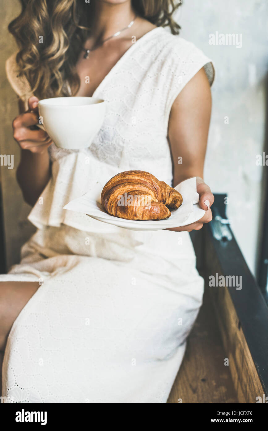 French or Italian breakfast. Young blond woman in white dress holding ...