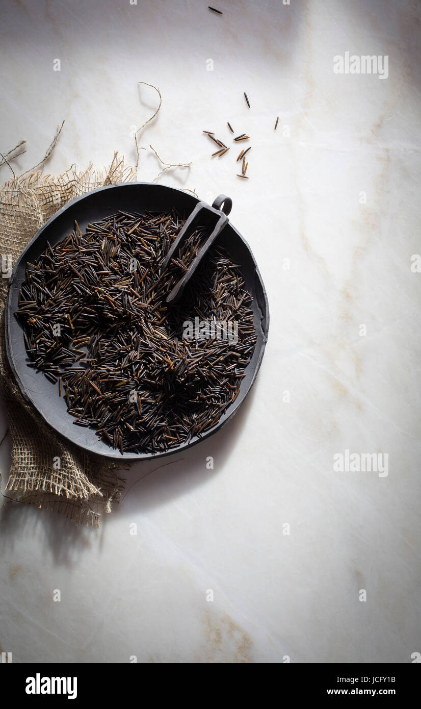 Wild rice in a ceramic black ceramic plate on a marble table on top ...