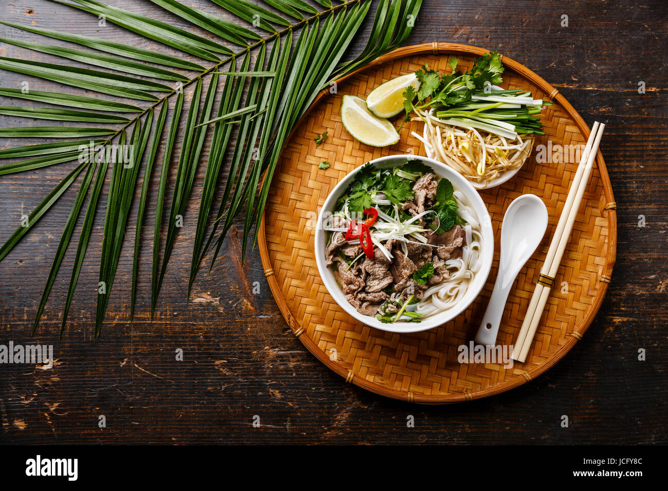 Pho Bo vietnamese Soup with beef on bamboo tray and palm branch on ...