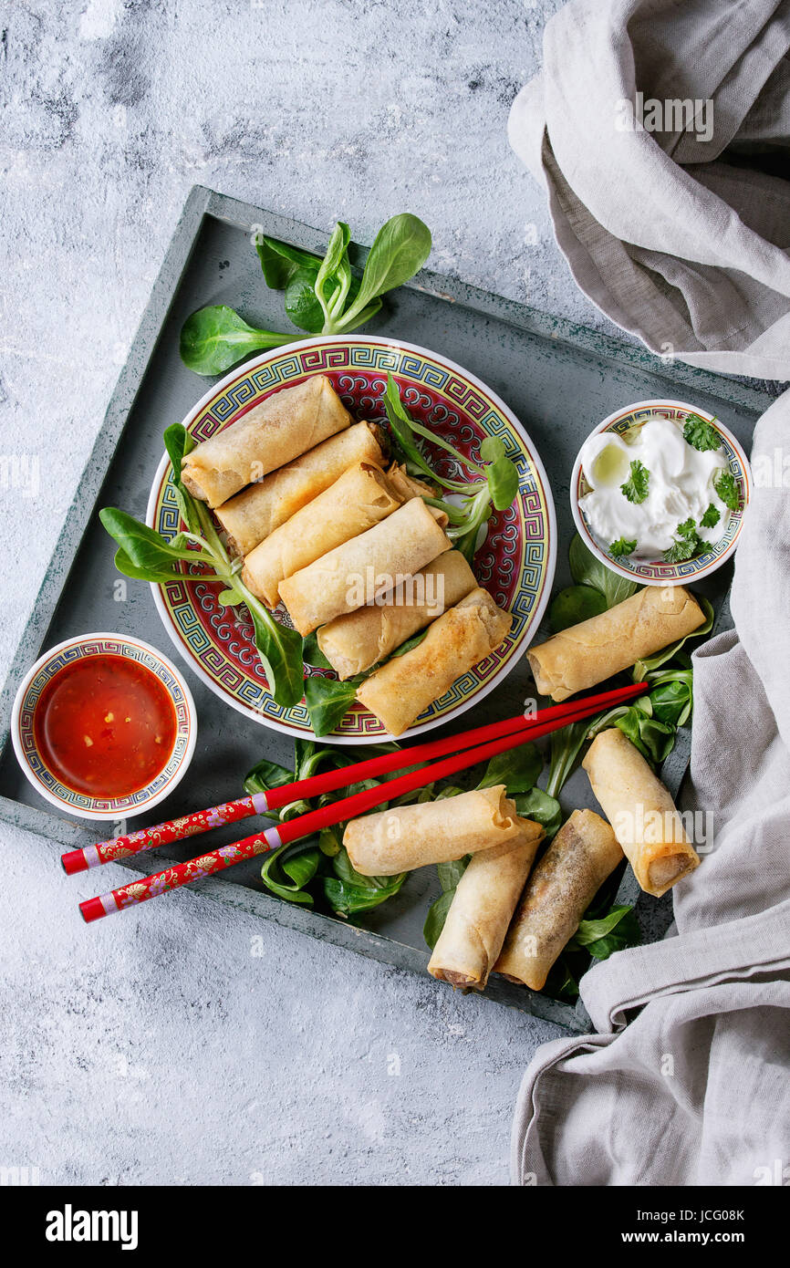 Fried spring rolls with red and white sauces, served in china plate on ...