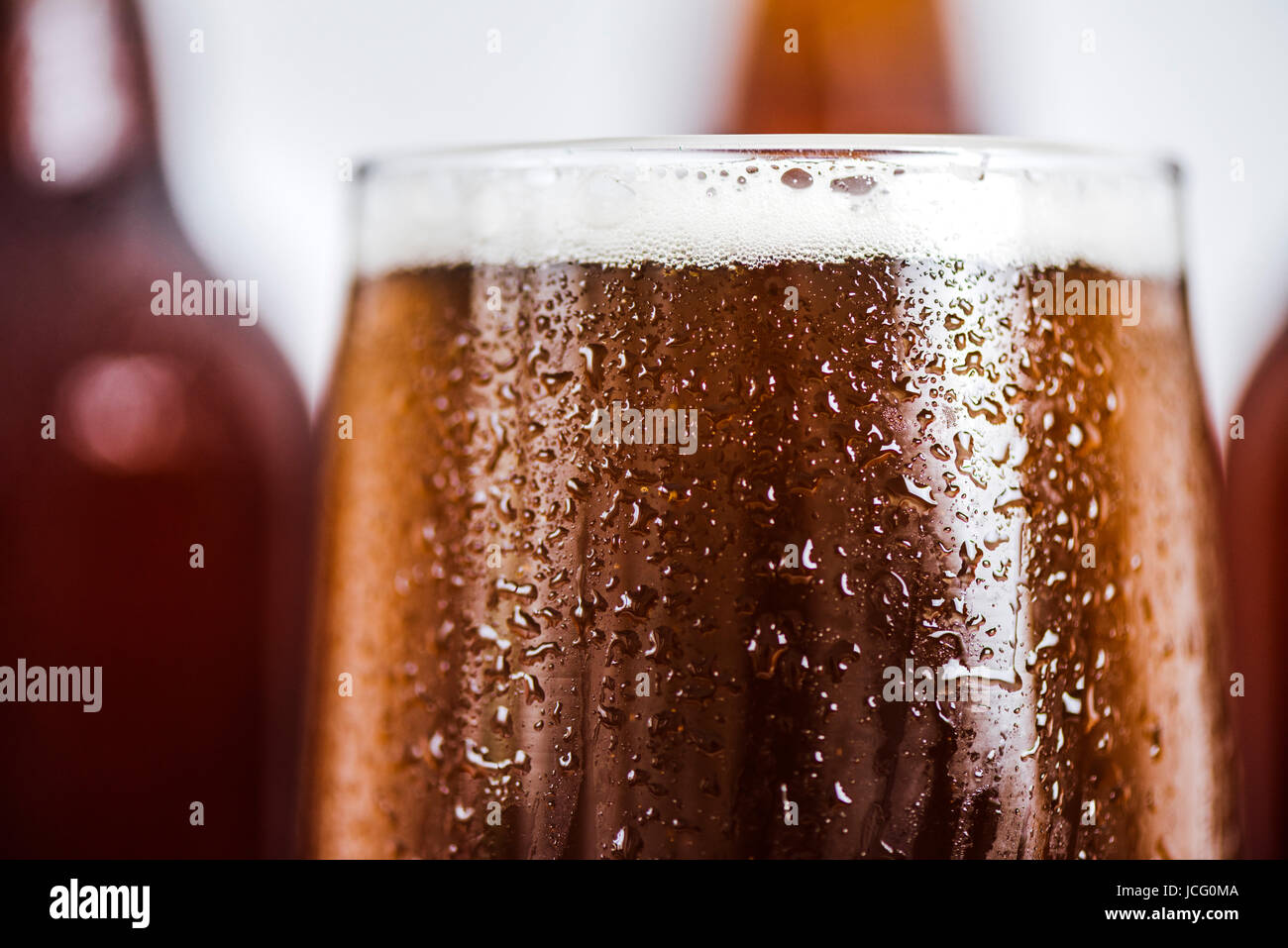 A glass of beer in front of beer bottles photographed from front view ...