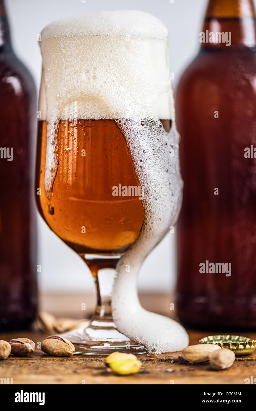 A glass of beer in front of beer bottles photographed from front view ...