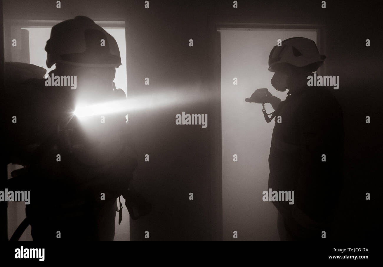 Fireman using a thermal imaging camera in a smoke filled room in a ...