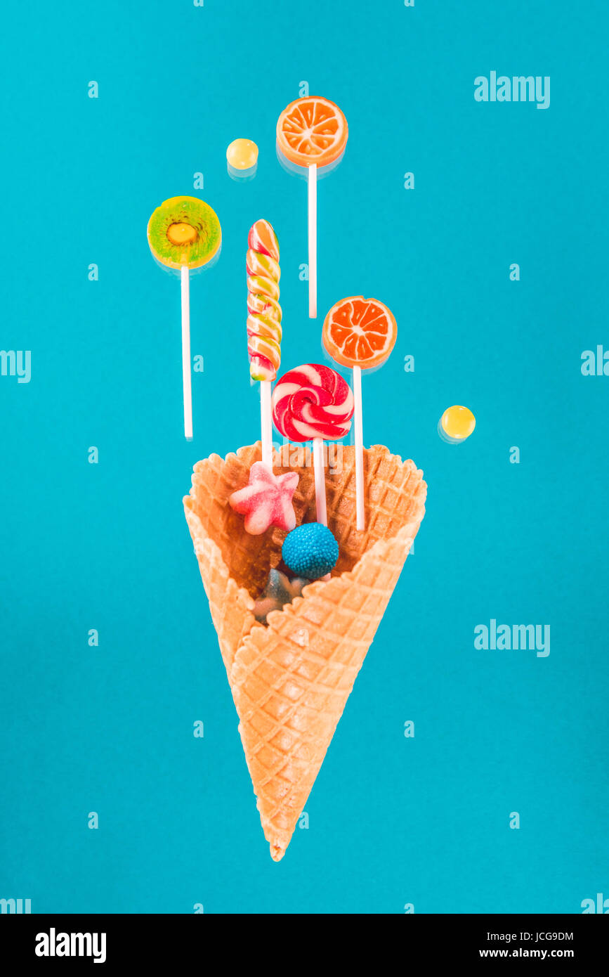 Close-up view of crispy waffle cone with sweet candies and lollipops on ...