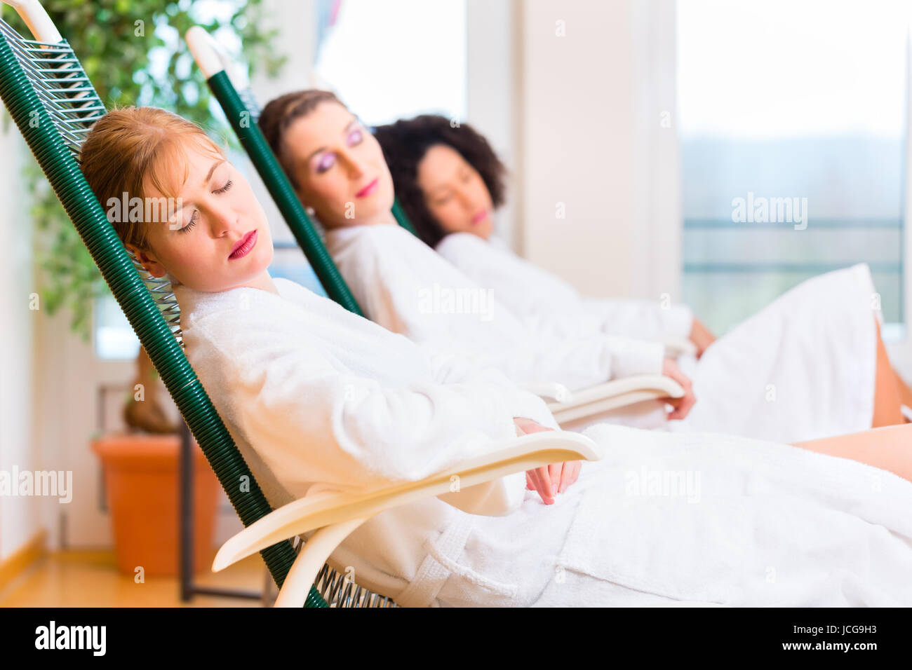 Friends relaxing and sleeping in relaxation room on lounger of wellness ...