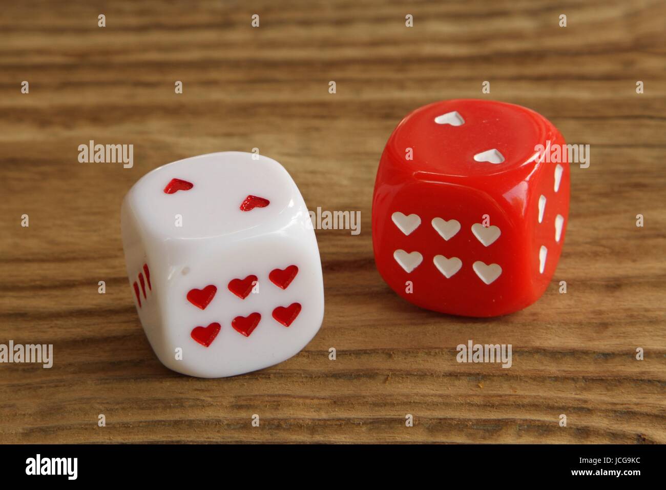 Red and White dice with hearts instead of numbers on wooden background ...