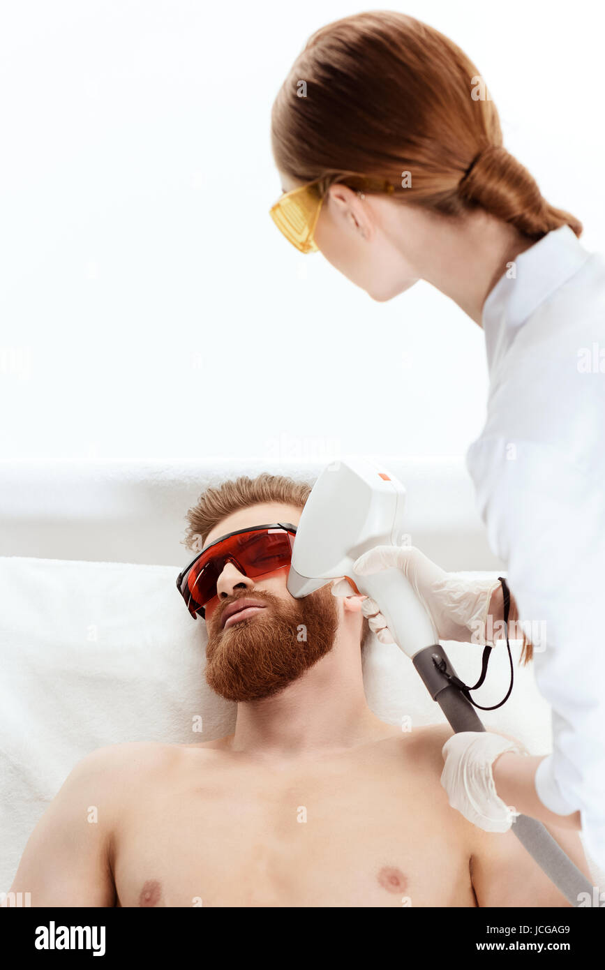 young man receiving laser skin care on face isolated on white. healthy ...